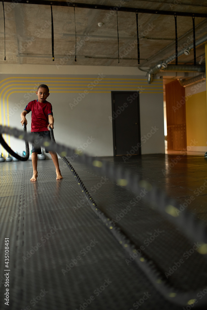 Vertical image of barefooted African boy in activewear exercising in ...