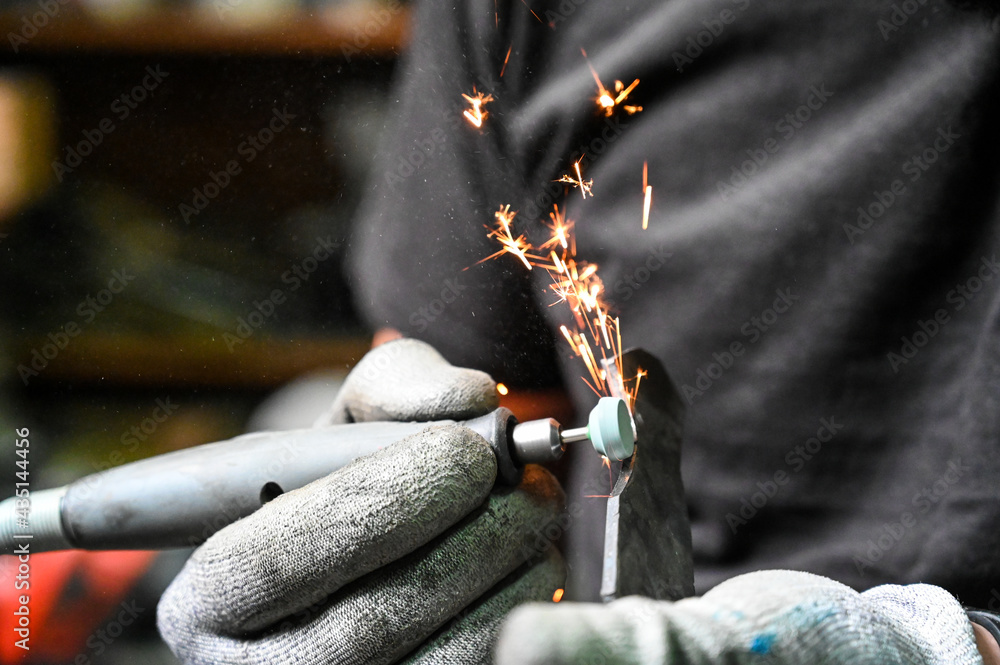 Die Grinder. Man hands grinding a metal at work. Sparks from the ...