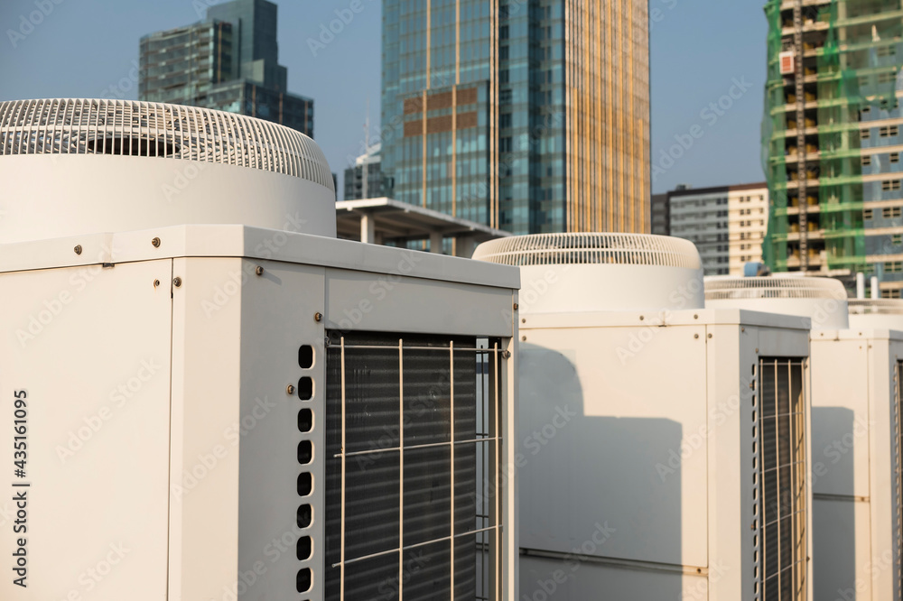 Rows of rooftop HVACs on the roof deck of an office tower with taller ...