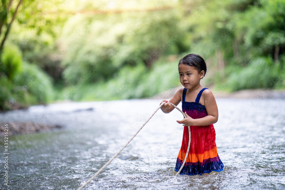 Cute little girl pulling rope at streams. Stock Photo | Adobe Stock
