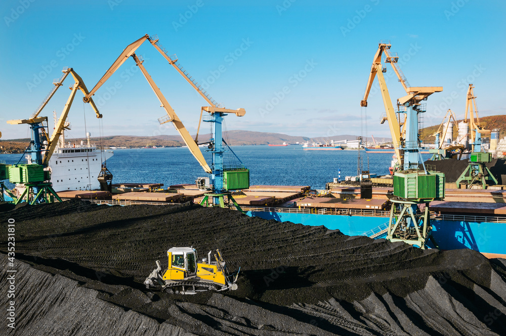 Loading of coal by buckets (grabs) of portal cranes into the holds of a ...
