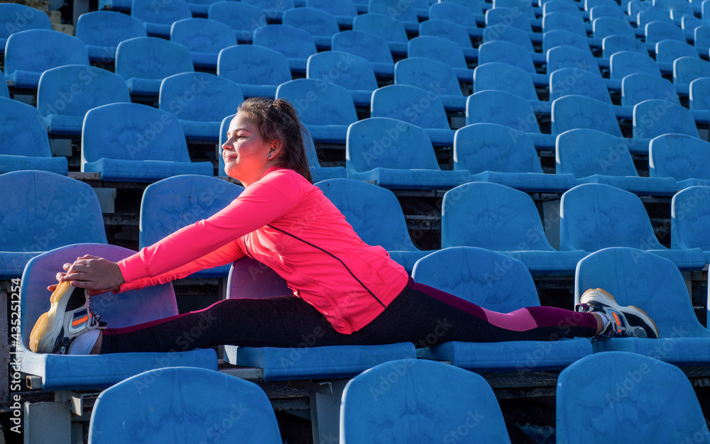 Flexible girl child in sportswear do splits stretching legs on stadium ...