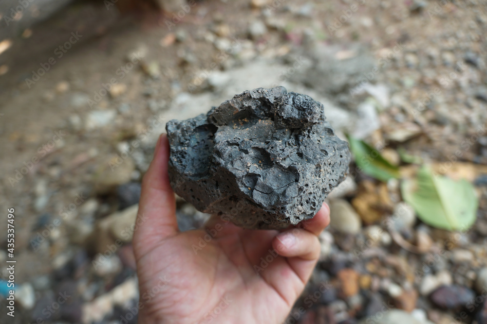 Basalt igneous rock in a hand. Basalt is a dark-colored, fine-grained ...