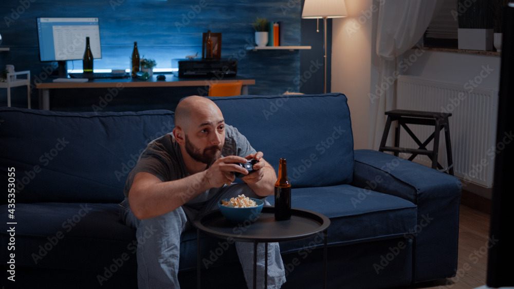 Competitive determined man playing videogame in living room at night ...