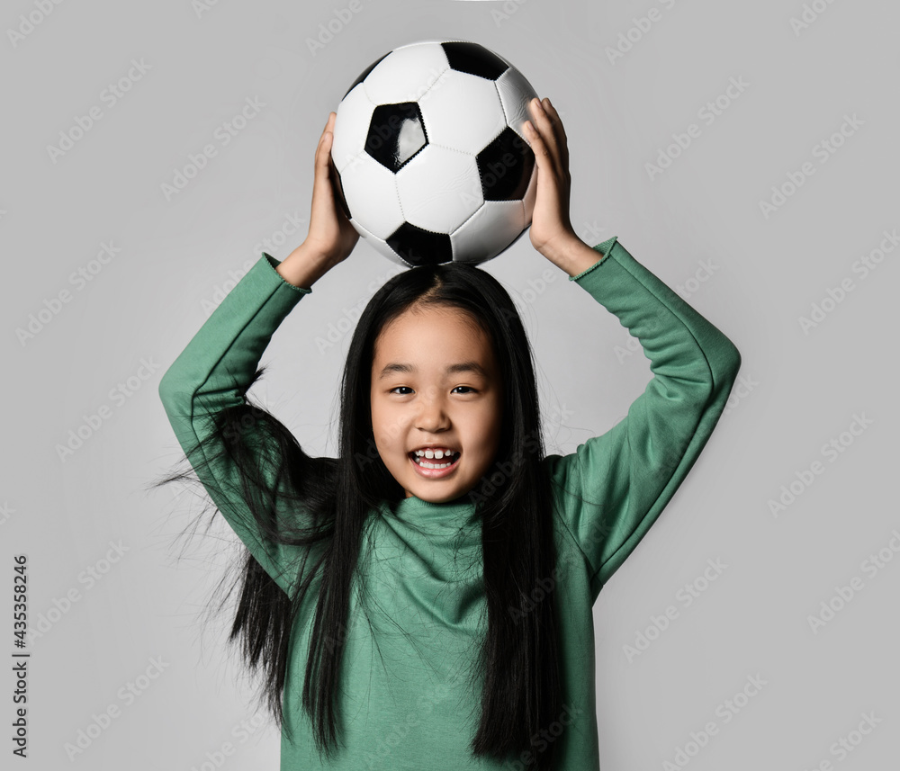 Young beautiful asian girl holding soccer football ball over her head ...