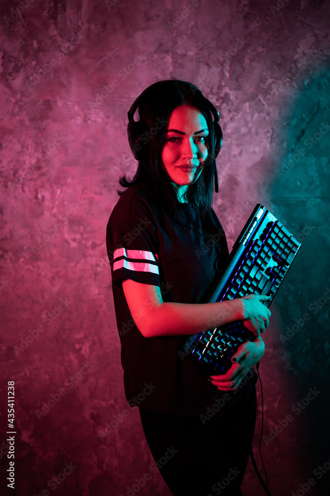 Female esports gamer posing with a gaming gear in neon light. Streamer ...