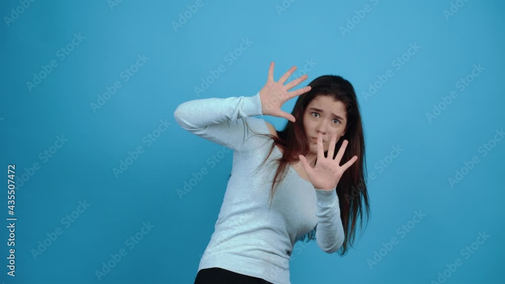 The frightened young woman raises her hands up and bends scared ...