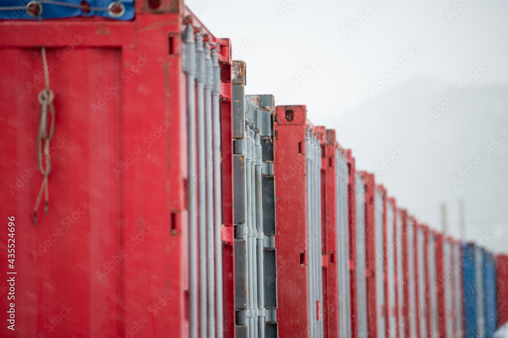 A row of large metal shipping containers at a seaport yard. The storage ...