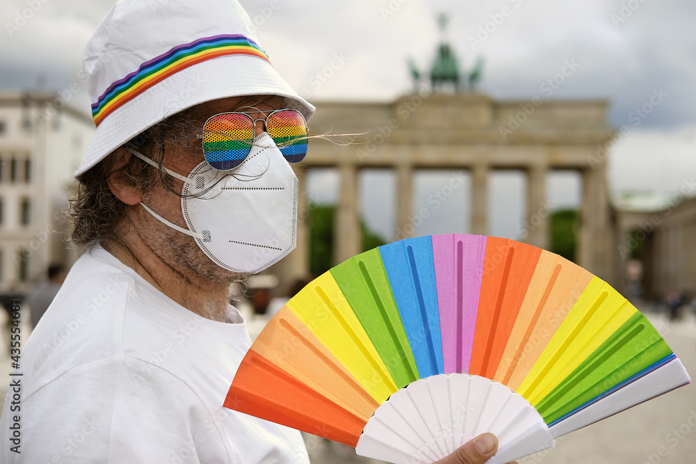 Mature Caucasian LGBT man in Berlin with rainbow fan and ribbon on ...