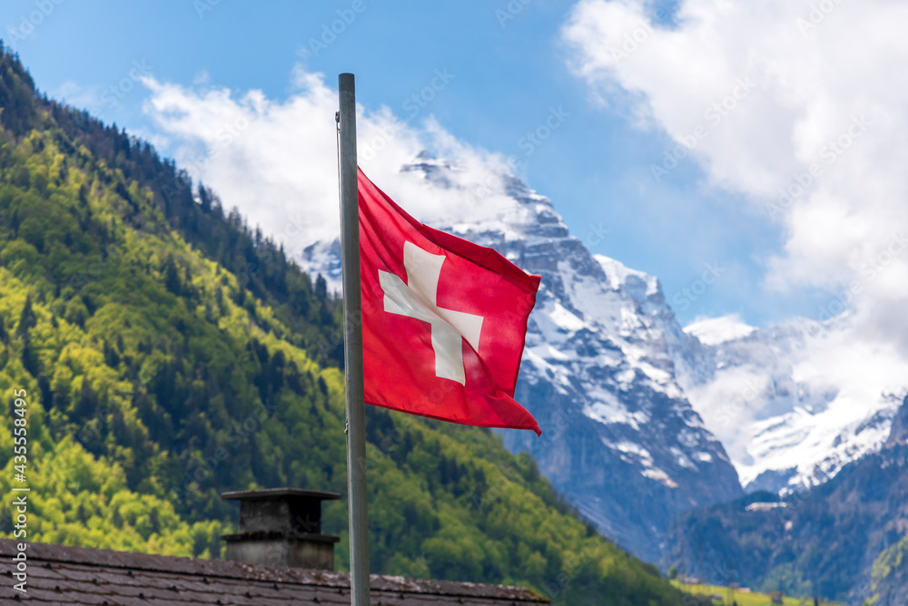 waving swiss flag in the swiss alps, with green and snow white ...