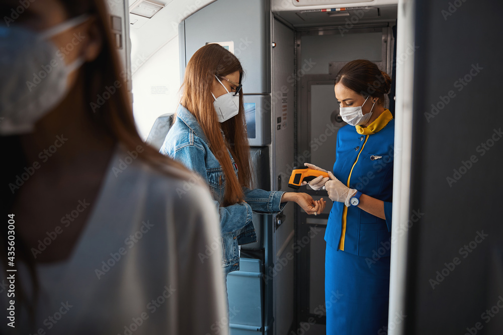 Cabin crew female holding temperature gun above female hand Stock Photo ...