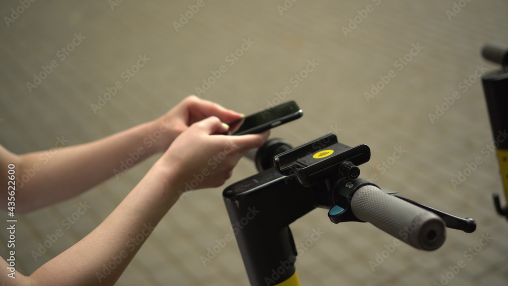 A young woman starts a ride on a sharing electric scooter. The girl ...