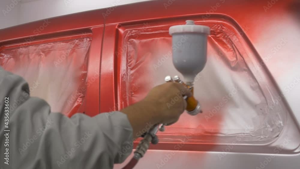 Car colouring process held by the worker. Repairman painting car with a ...