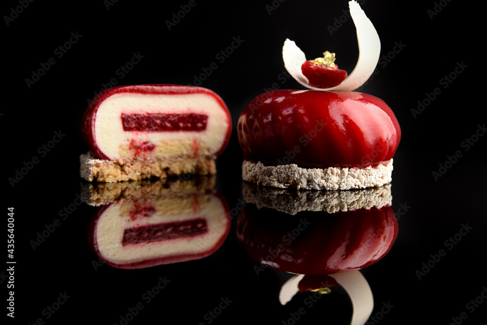 Round cake in red glaze decorated with pieces of coconut on a black ...