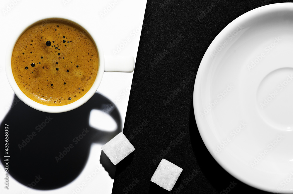 Cup of coffee and lump sugar with shadow on black and white bacrground ...