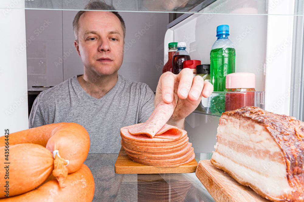 Open fridge from the inside, glass shelves with different kinds of meat ...