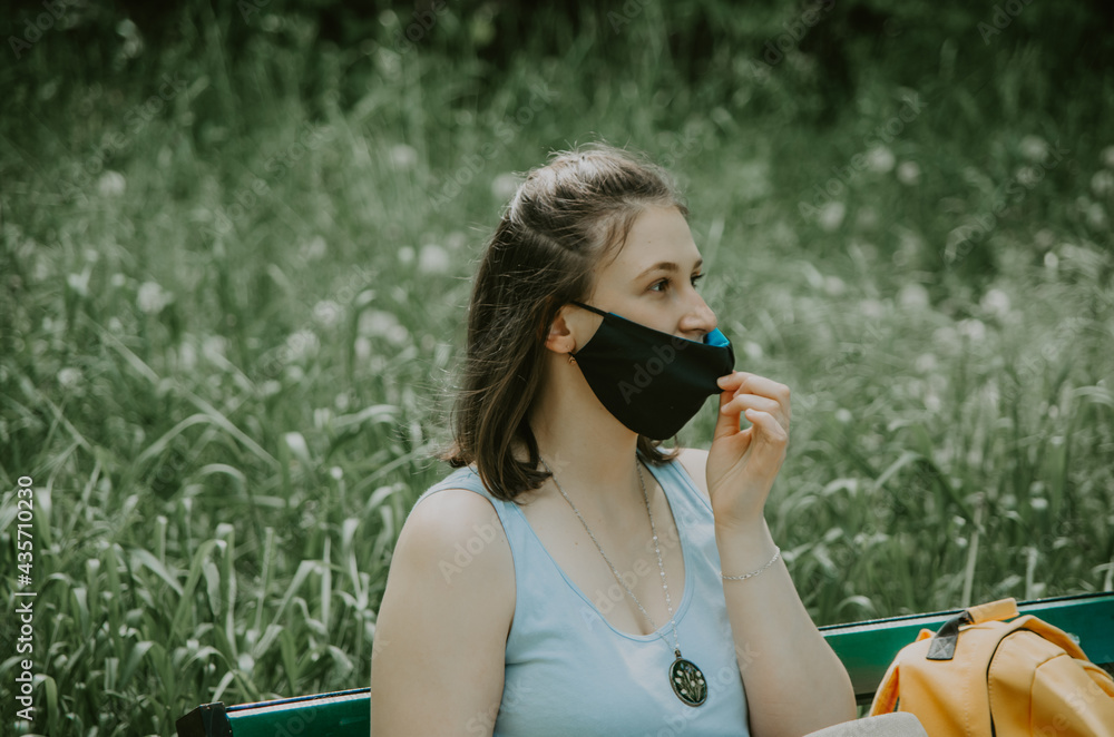Side view close up of young woman taking the face mask off for a gulp ...