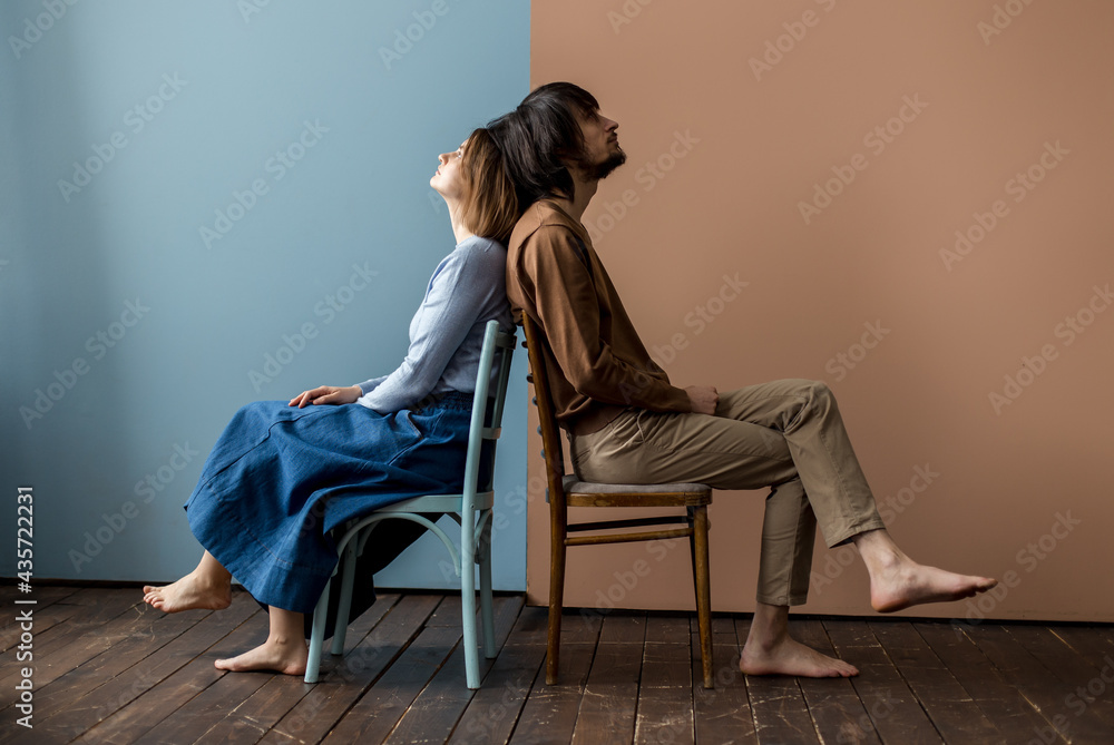 Guy and girl sit back to back on a chair. Background is divided into ...