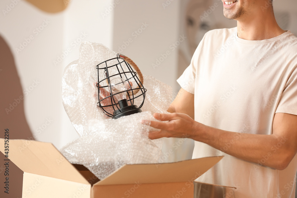 Young man unpacking box at home Stock Photo | Adobe Stock