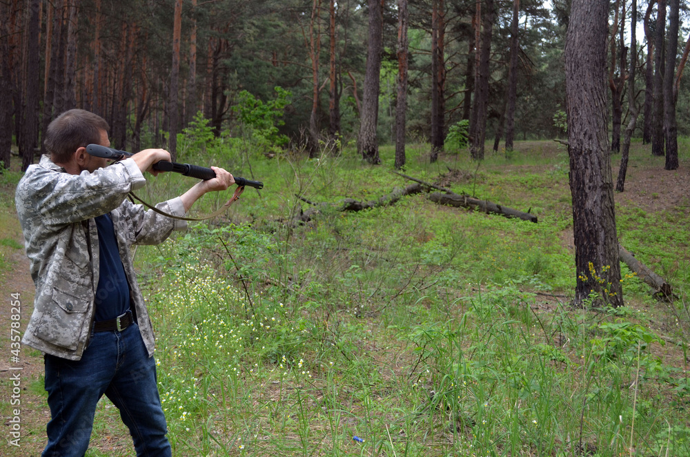 Man with 12-gauge rifle (pump action shotgun). Unformal shooting range ...