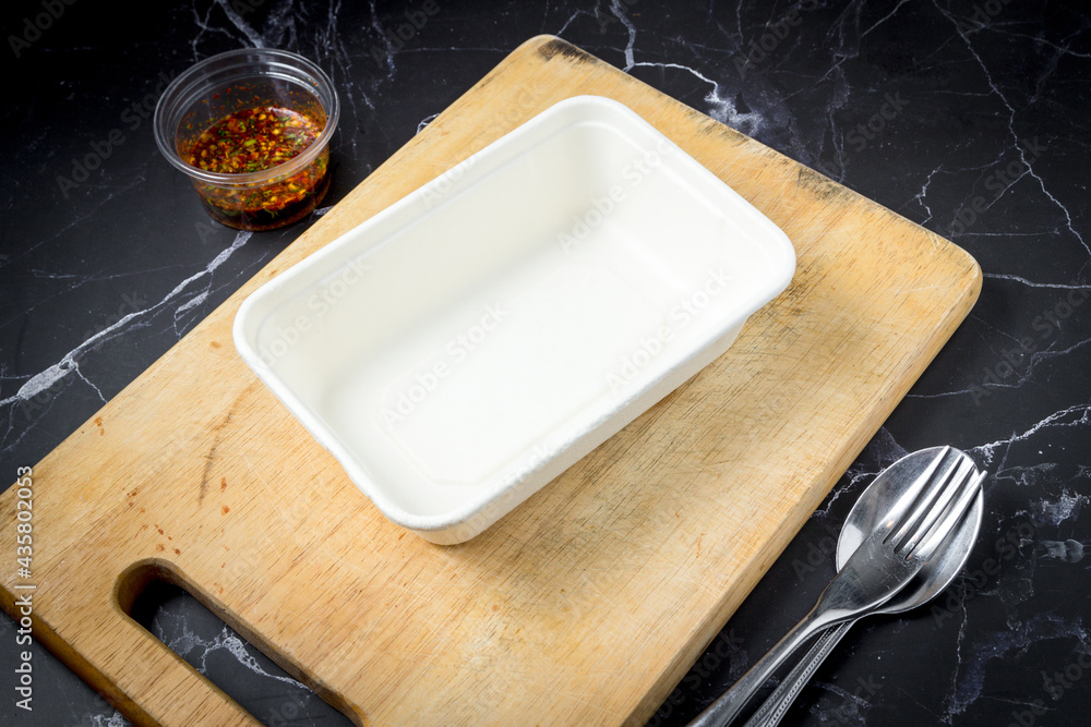 The empty rice box was placed on a cutting board with cutlery and ...