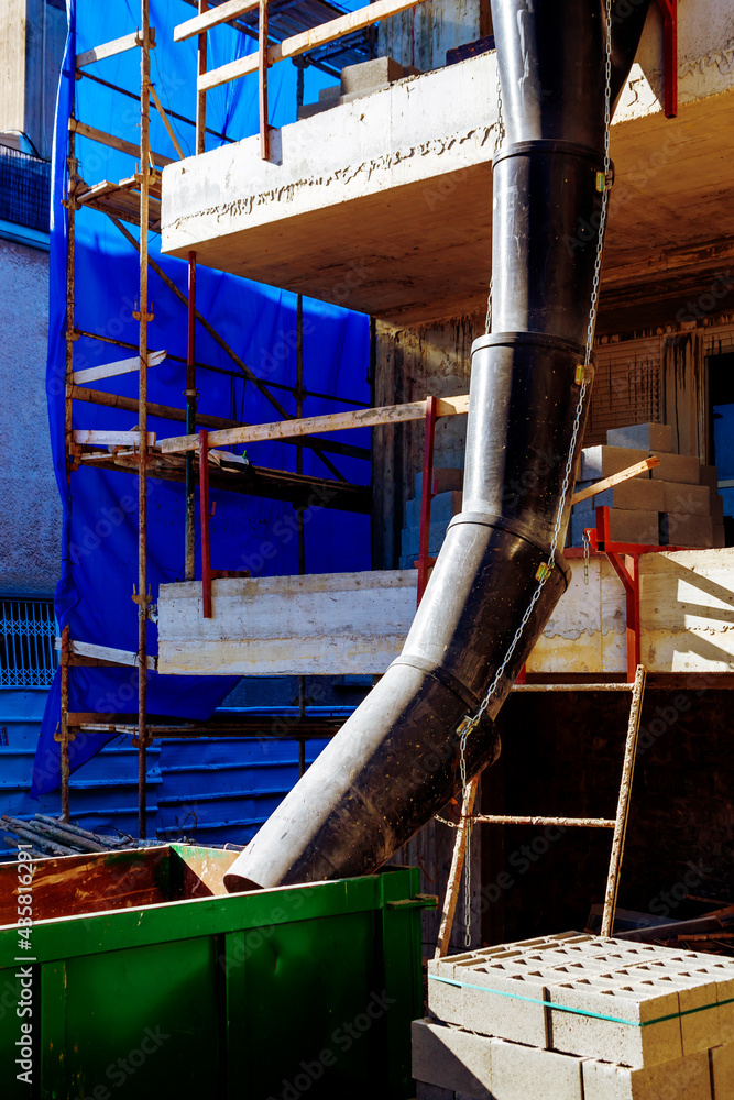 Suspended sections of black garbage chute on a facade of building under ...