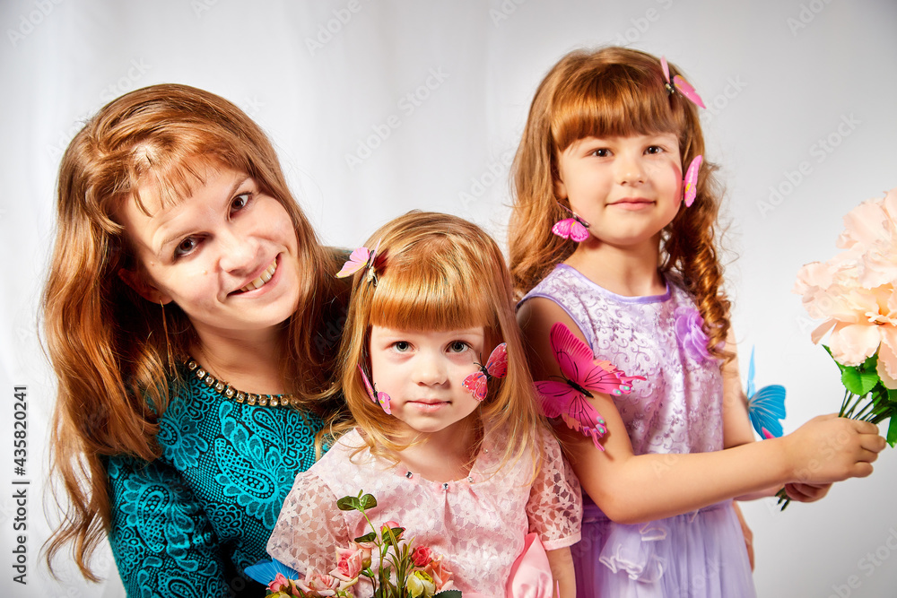 Cute daughters and mother with flowers in the studio on a white ...