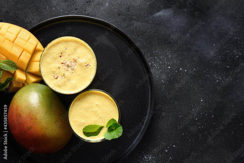 Indian traditional cold mango lassi or smoothies on black background ...