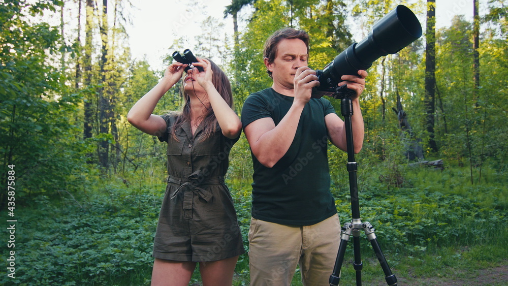 Birdwatching in park. Couple watch birds with binoculars and camera ...