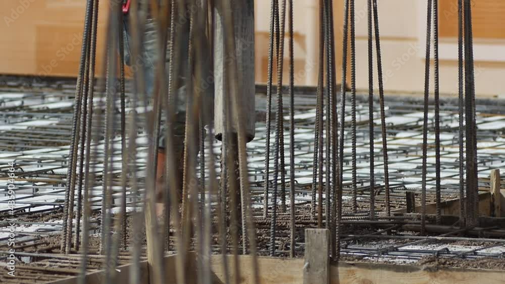 Iron rebar grids and construction worker. Man pouring fresh concrete at ...