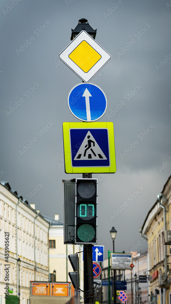 City, street, pillar with few road signs and traffic light close-up ...