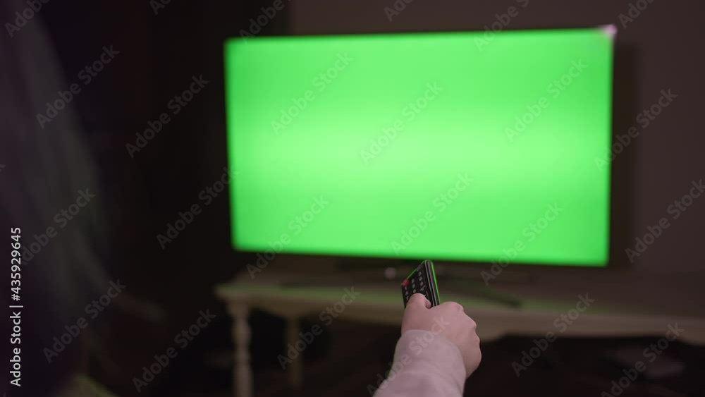 Girl switches channels by pressing the buttons on the remote control ...