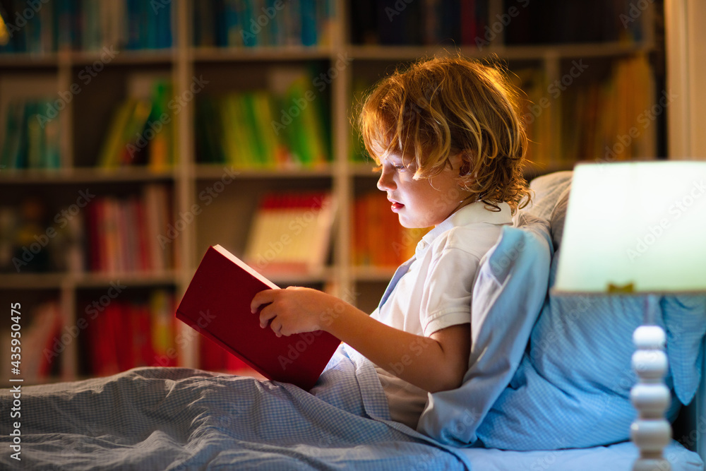 Child reading book in bed. Kids read at night. Stock Photo | Adobe Stock