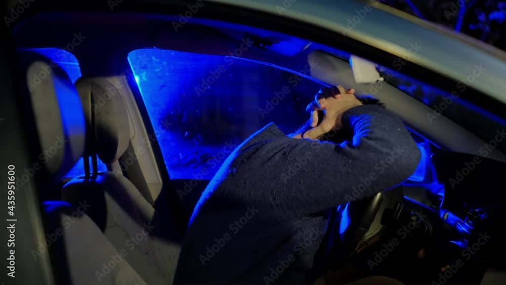 Drunk driver in black sweater inside car salon looks at flashing police ...