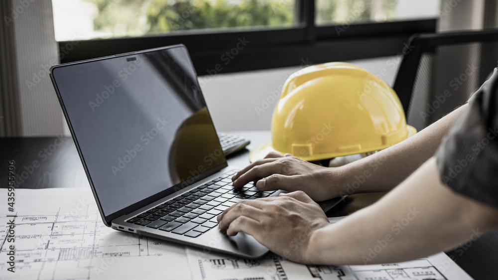 Young man with a laptop plotting a system of building structures in ...