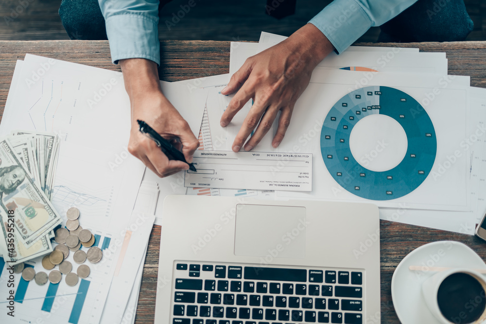Foto de Business man hand writing and signing white blank bank check ...
