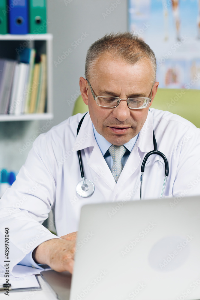 Calm Family Medical Doctor in Glasses is Working on a Laptop Computer ...