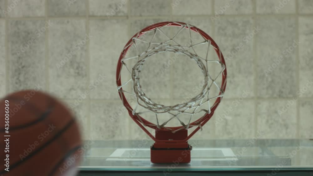 Static shot of a scored basket, the ball passing through the hoop from ...