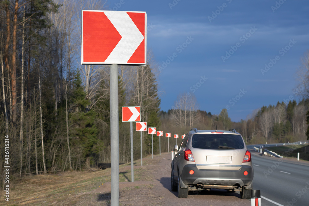 The road sign is a sharp turn of the road to the right and the car in ...