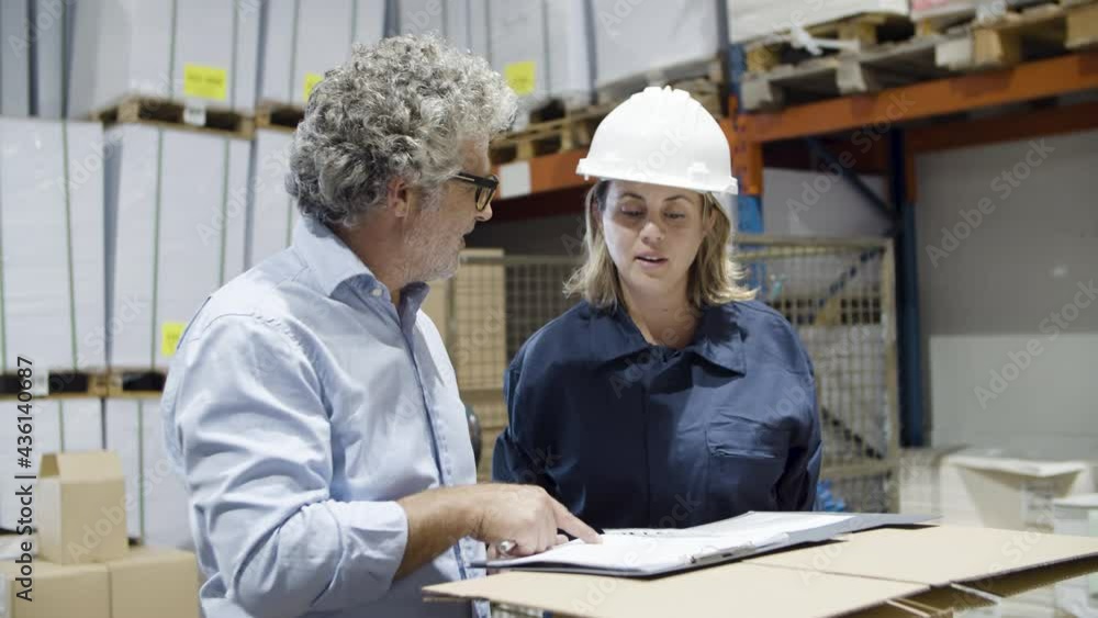 Focused supervisor and female employee talking in warehouse. Caucasian ...
