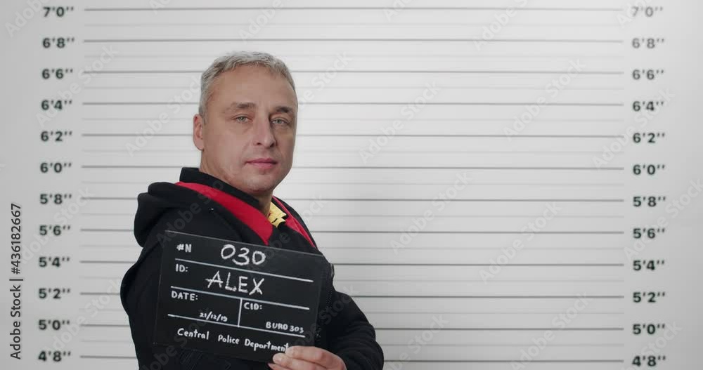 Side profile mugshot of male criminal holding sign while being ...