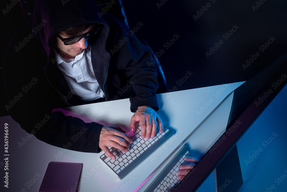 A man in a black hoodie at the computer. The man at the computer is ...