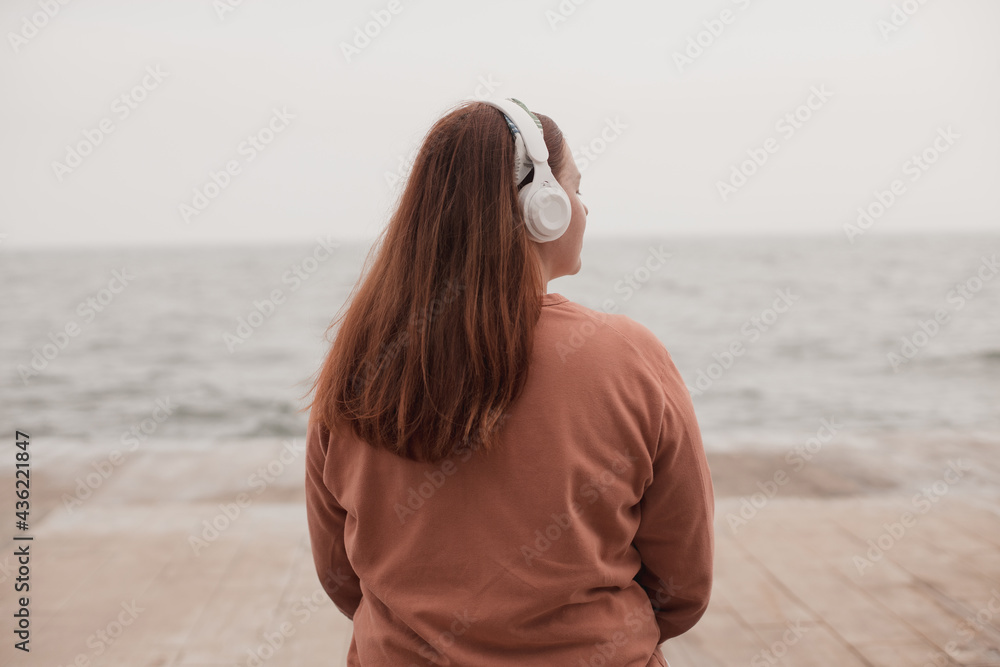 Relaxed cute girl listening to music on the beach at sea background ...