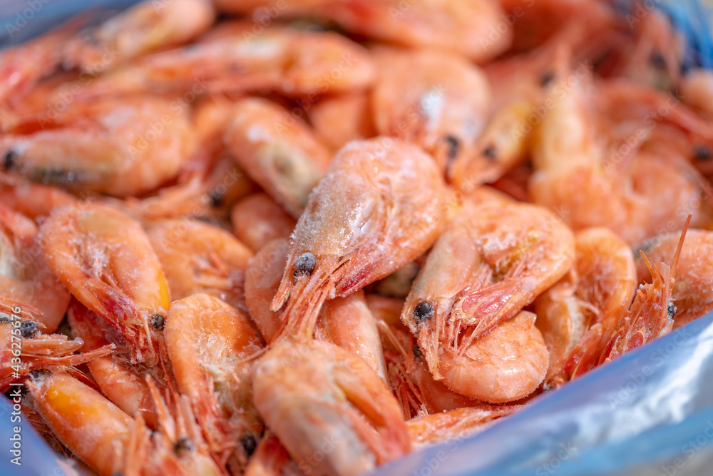 Pre-cooked and frozen shrimp close-up in a blue plastic bag. Dry ...