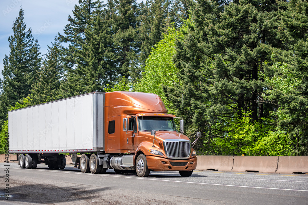 Stylish brown big rig semi truck with chrome grille transporting cargo ...