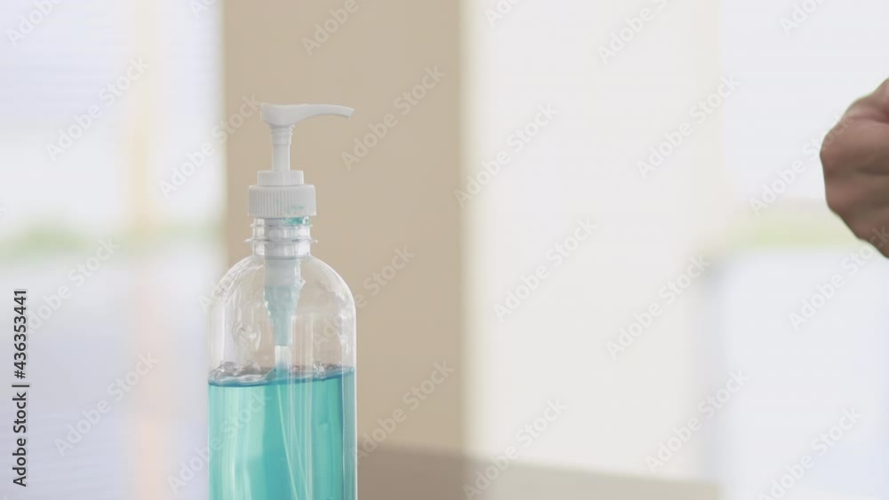Close up of a man's hand pressing a bottle of sanitizers cleansing ...