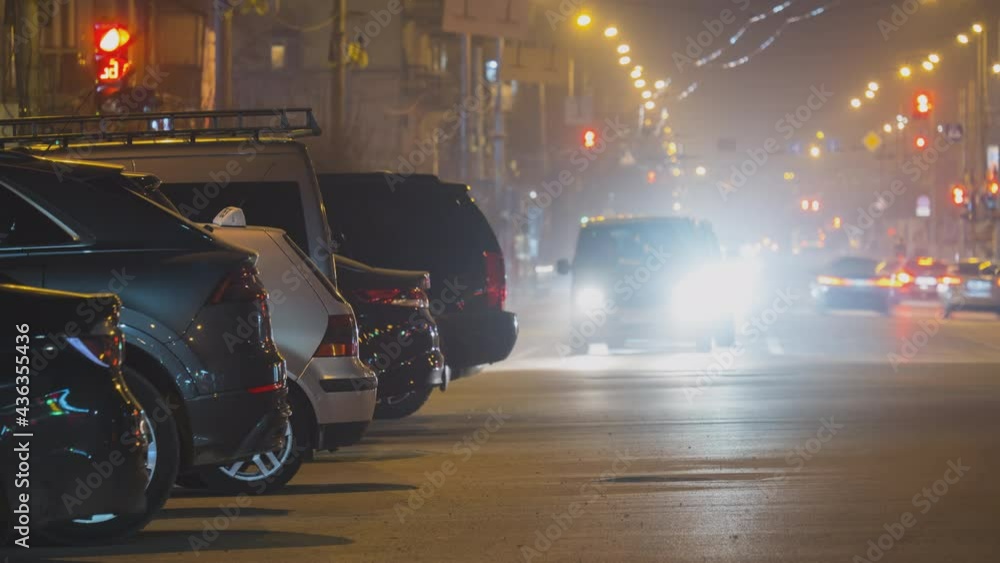 Close up of parked cars on roadside at night with blurred view of ...