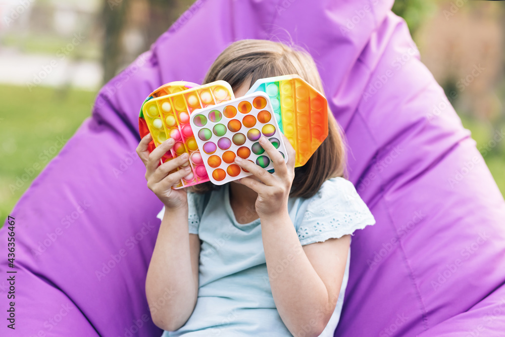 Portrait little girl with a modern popit toy. Colorful and bright pop ...