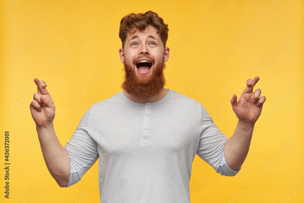 indoor shot of young male with a big beard and red hair, looks upwards ...