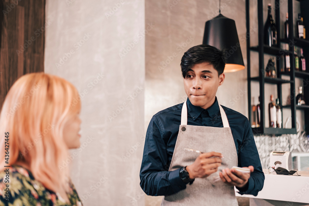 A Filipino waiter takes an order from a pretty young customer at a ...